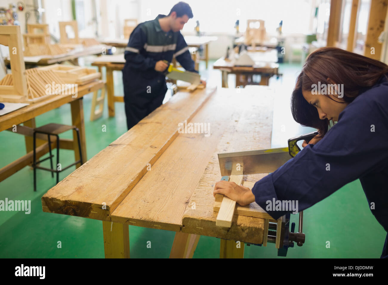 Focused trainee and instructor sawing wood Stock Photo - Alamy