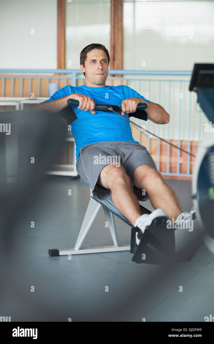 Determined man working out on row machine in fitness studio Stock Photo ...