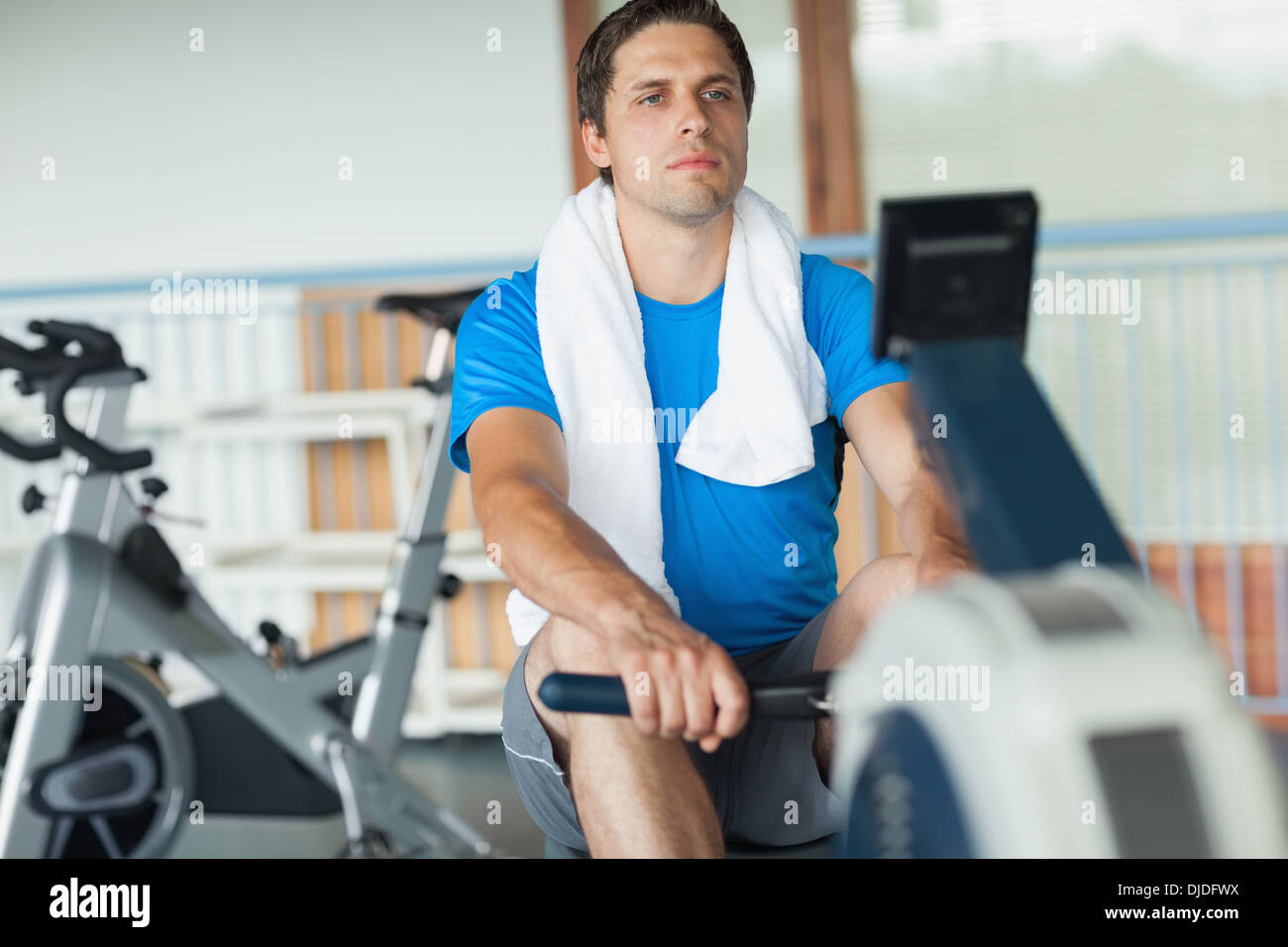 Determined young man working out on row machine Stock Photo - Alamy