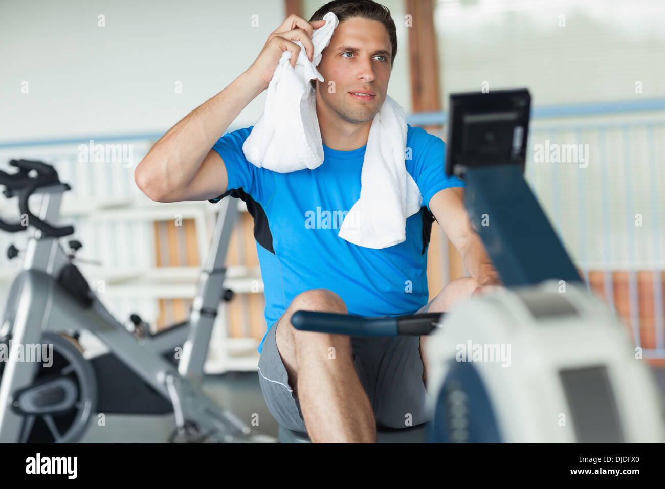 Tired young man working out on row machine Stock Photo - Alamy