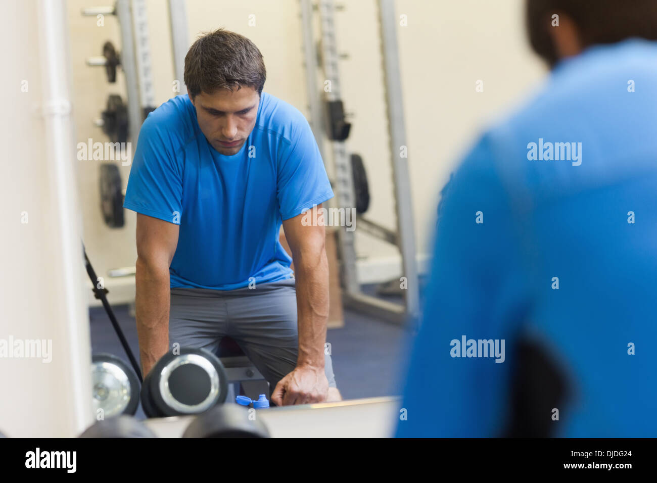 Tired young man sitting in gym Stock Photo - Alamy