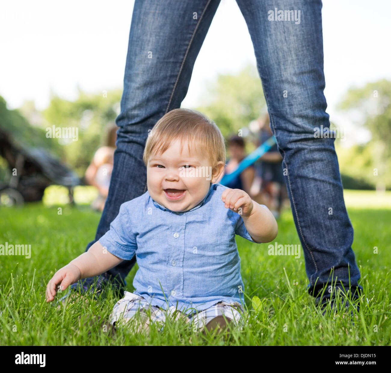 Cute Baby Boy Sitting In Front Of Mother In Park Stock Photo - Alamy