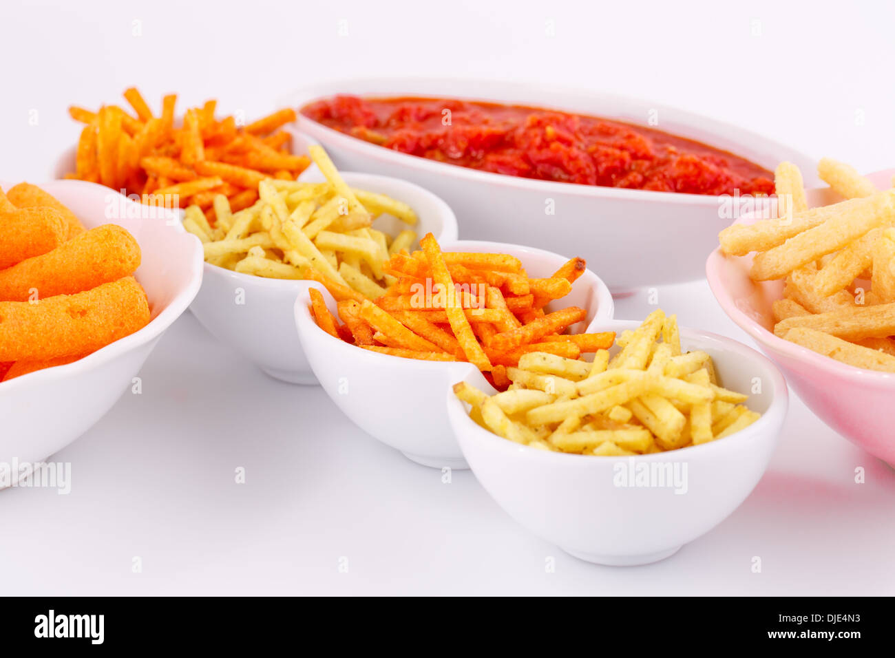 Potato, corn and wheat chips in bowls and red sauce isolated on gray ...