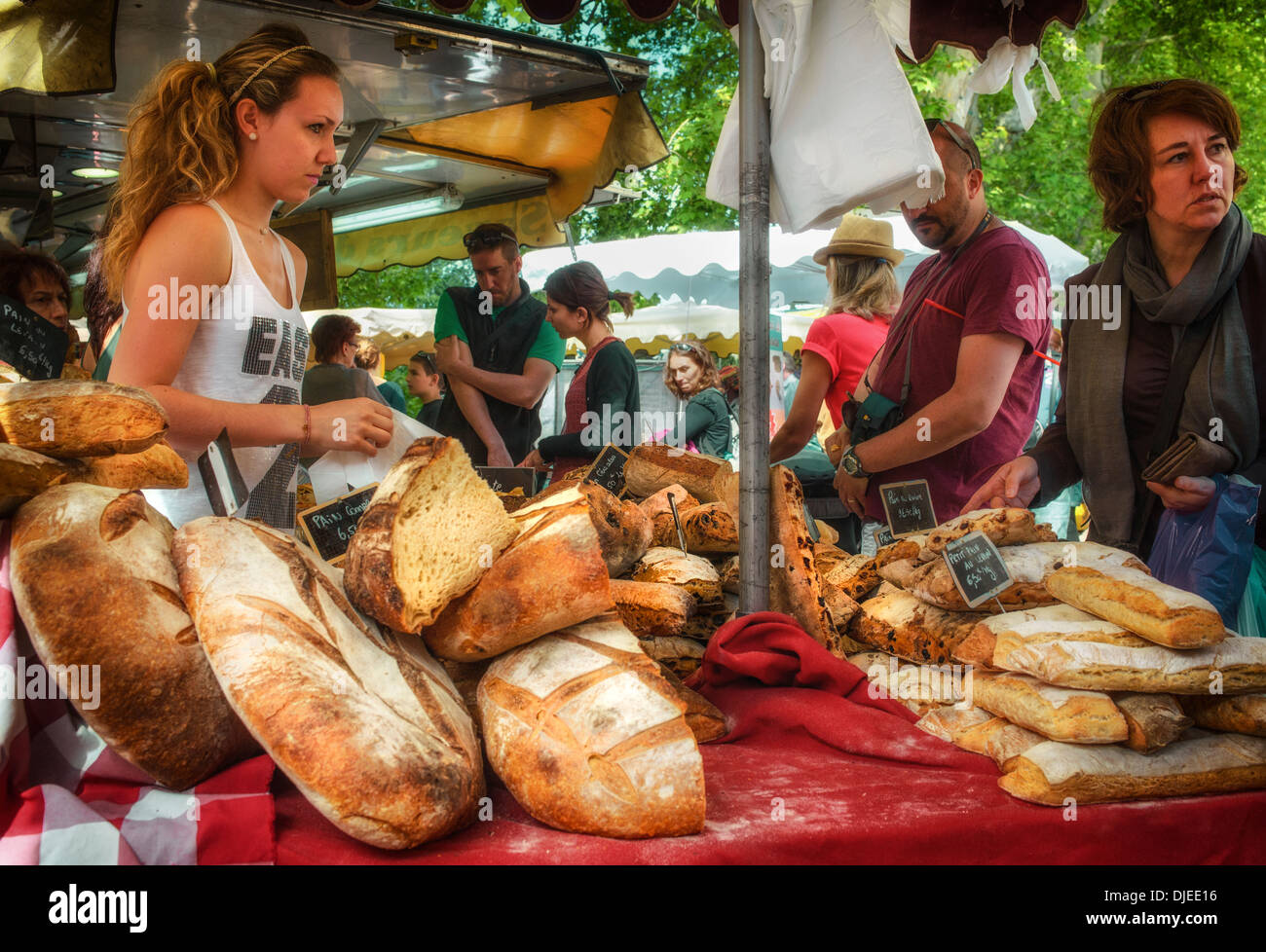 Woman selling artisan bread at a market stall in Lourmarin, France ...