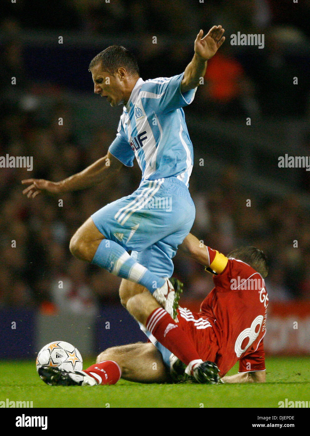 Steven Gerrrad of Liverpool plays the ball while tackling Benoit ...