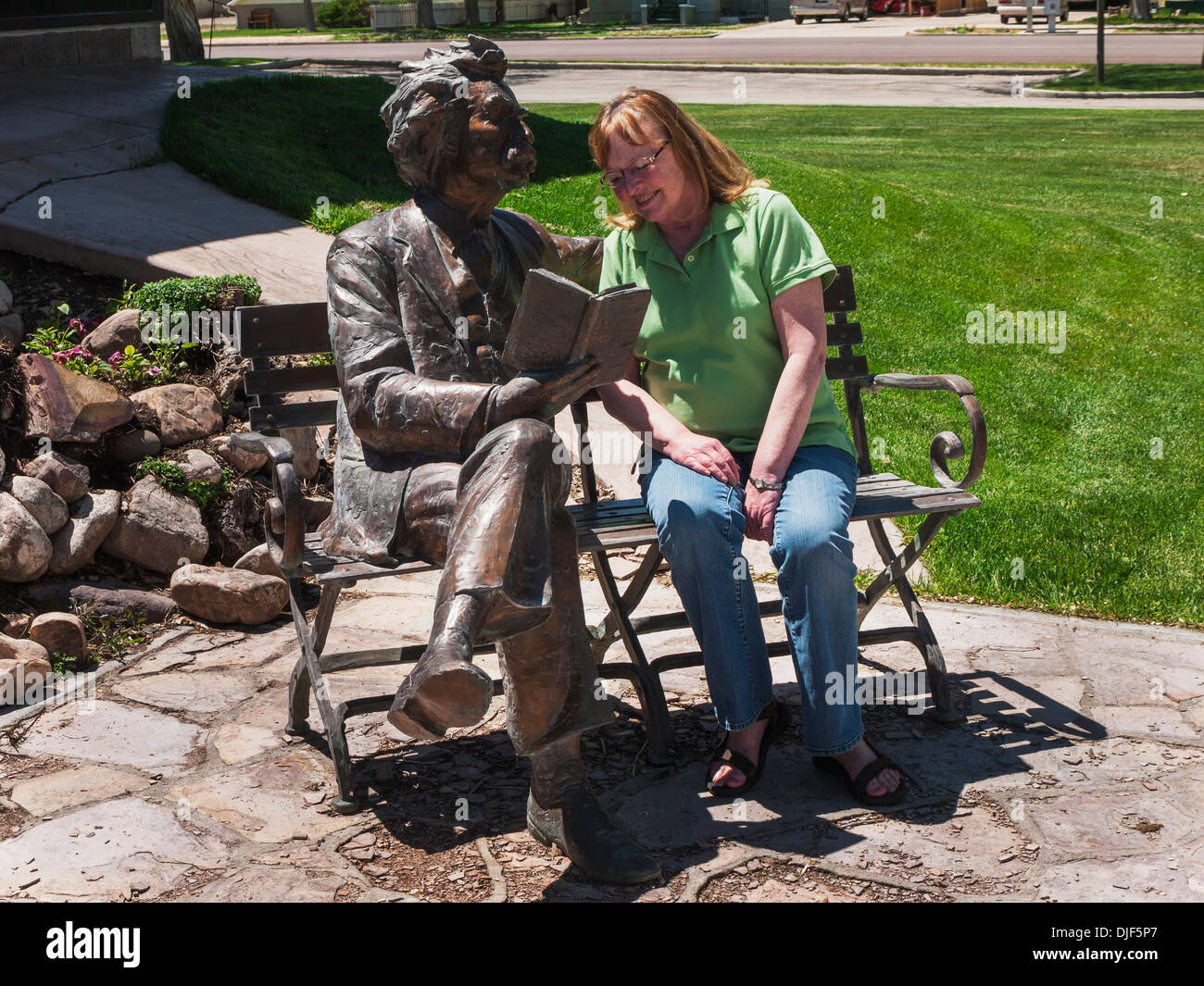 A Woman Sits On A Park Bench With A Statue Of Mark Twain Outside The ...