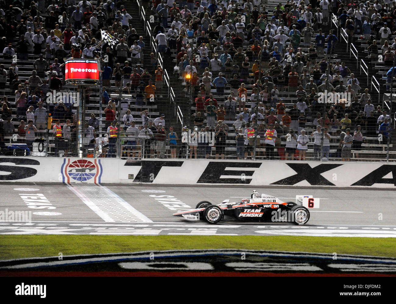 Ryan Briscoe of Team Penske crosses the finish line under the checkered ...