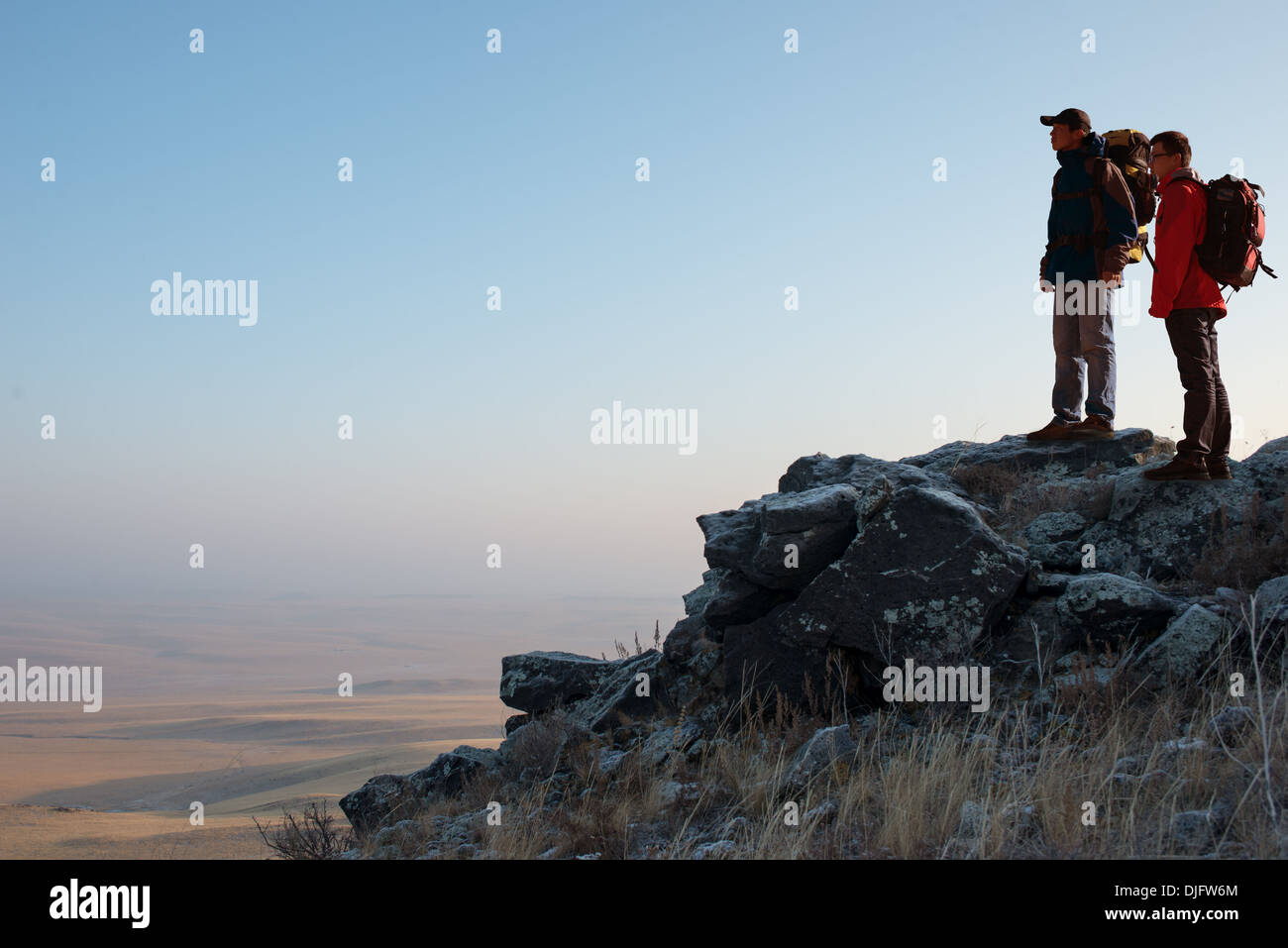 Two hikers enjoying sunrise from top of a mountain Stock Photo - Alamy