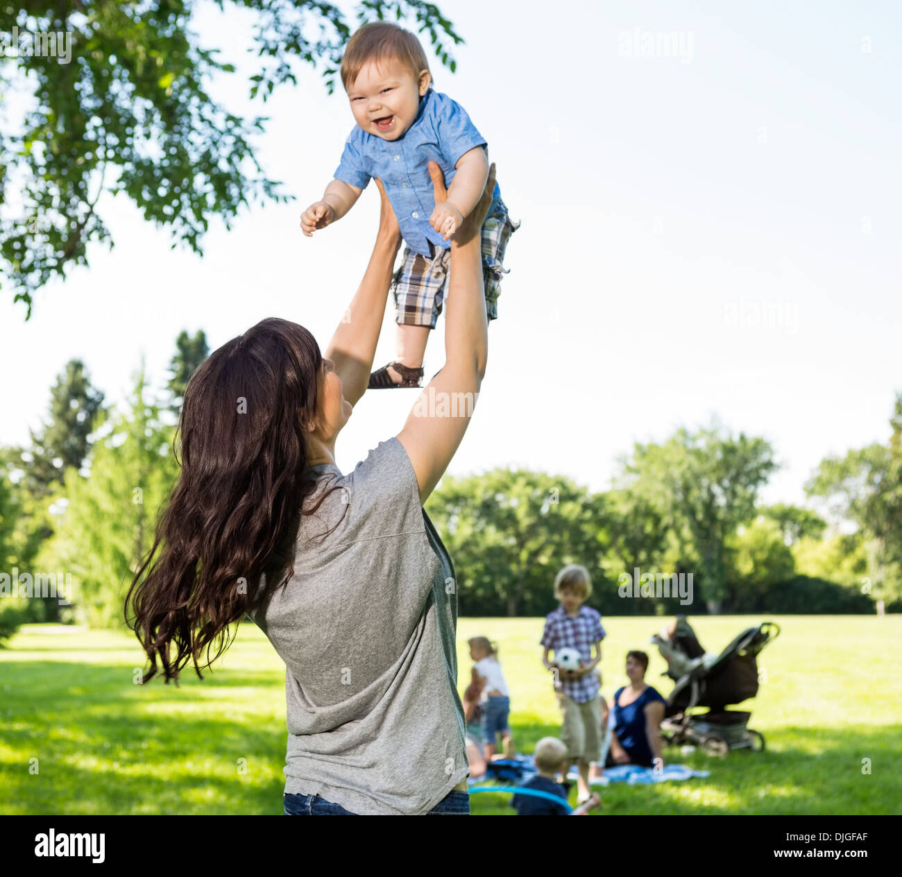 Playful Mother Lifting Baby Boy In Park Stock Photo - Alamy