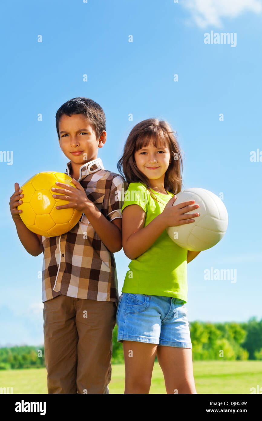 Couple of kids 6 years old, boy and girl holding balls in the park ...
