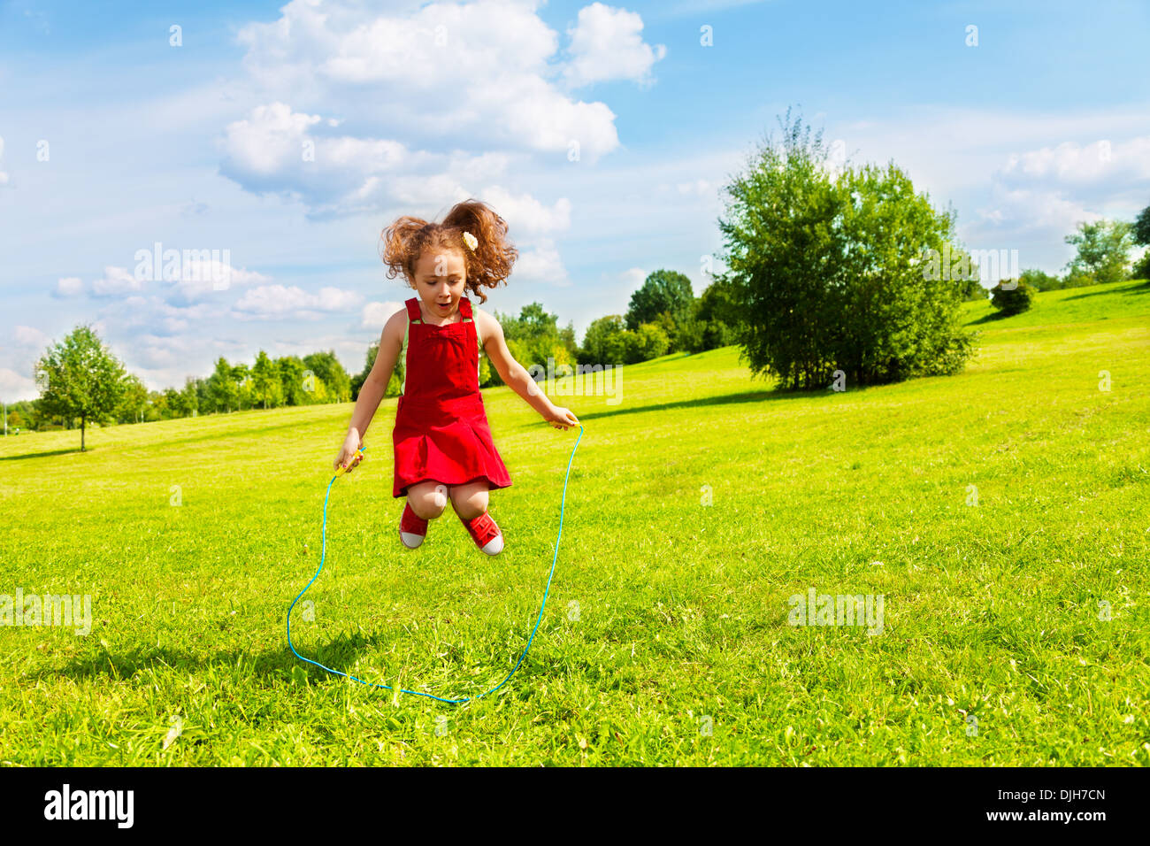 Beautiful little 6 years old girl jumping over the rope in the park on ...