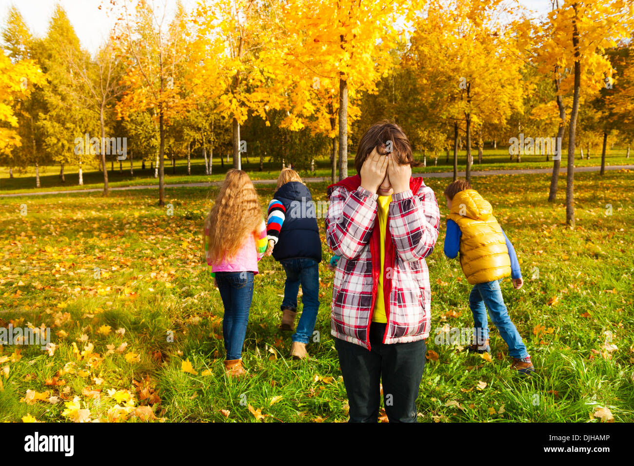 Kids play hide and seek with boy counting and friends running away Stock Photo - Alamy