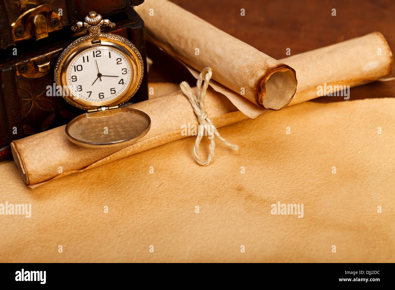 A desk with treasure box, old paper rolls and pocket watch with open ...
