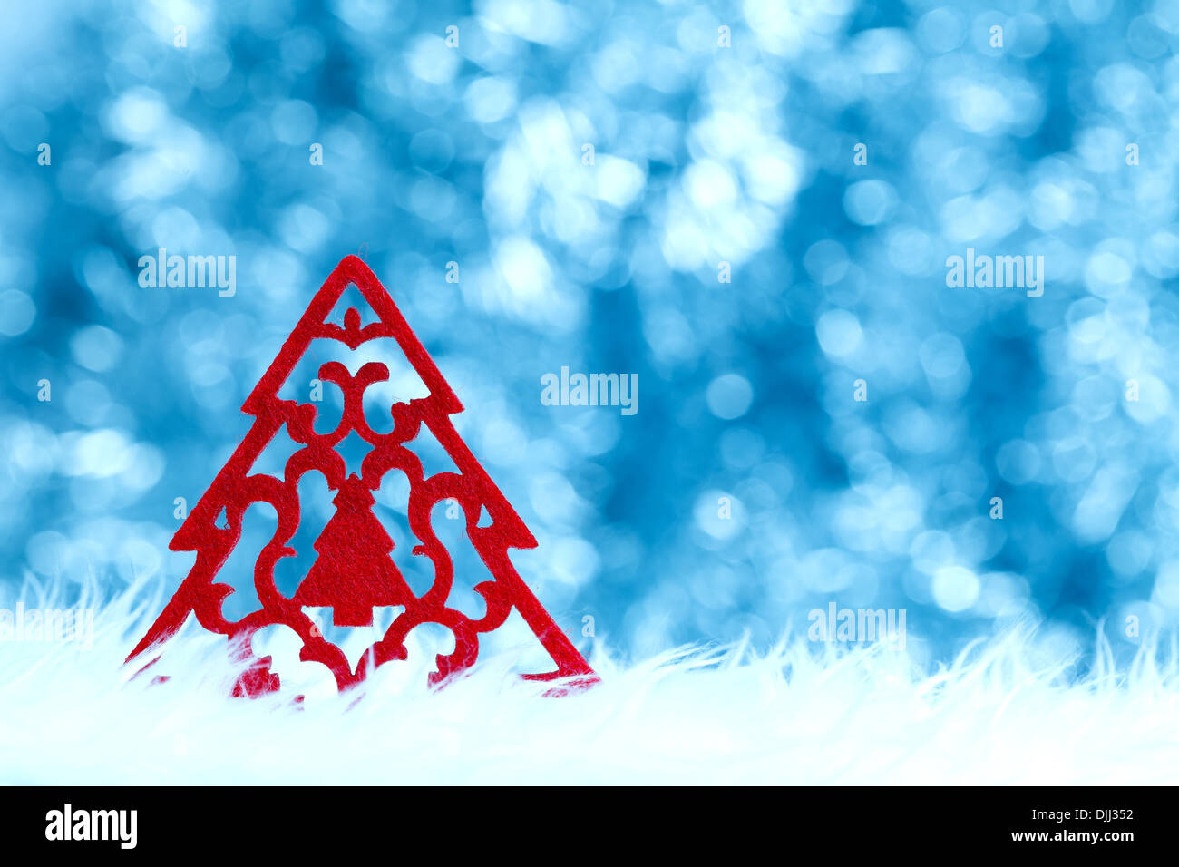 Little red Christmas tree on the left side with shiny blue background ...