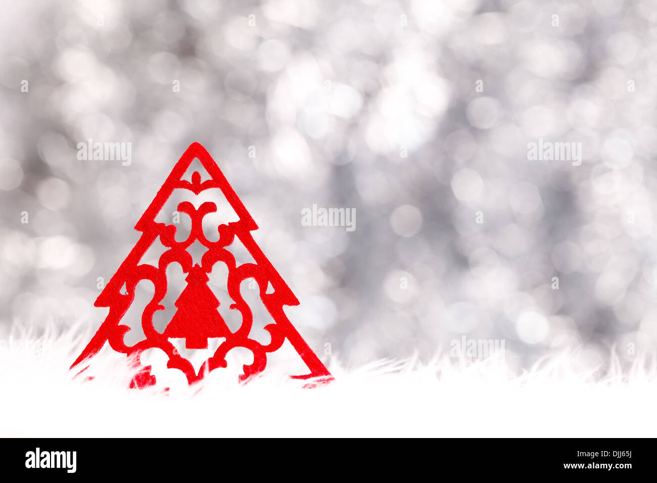 Little red Christmas tree on the left side with shiny silver background ...