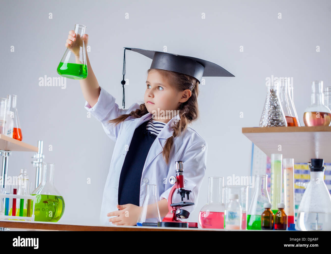 Serious chemist looking at reagent in flask Stock Photo - Alamy