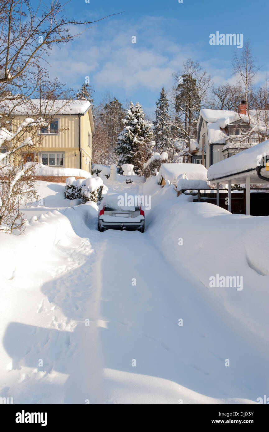Unploughed driveway after a heavy snowfall. Snow-covered car at the end ...
