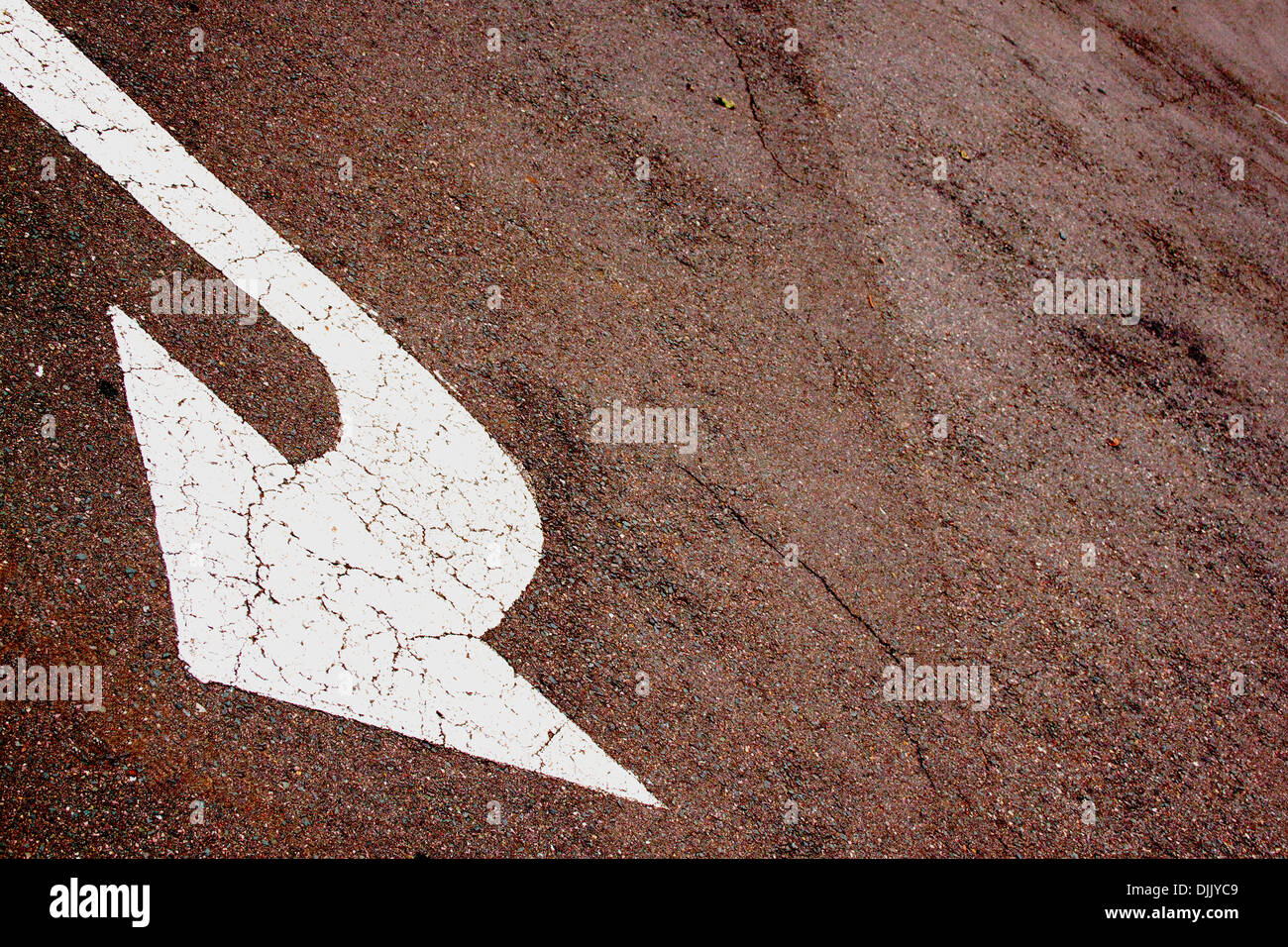 sloping white painted arrow on tarmac road surface Stock Photo - Alamy