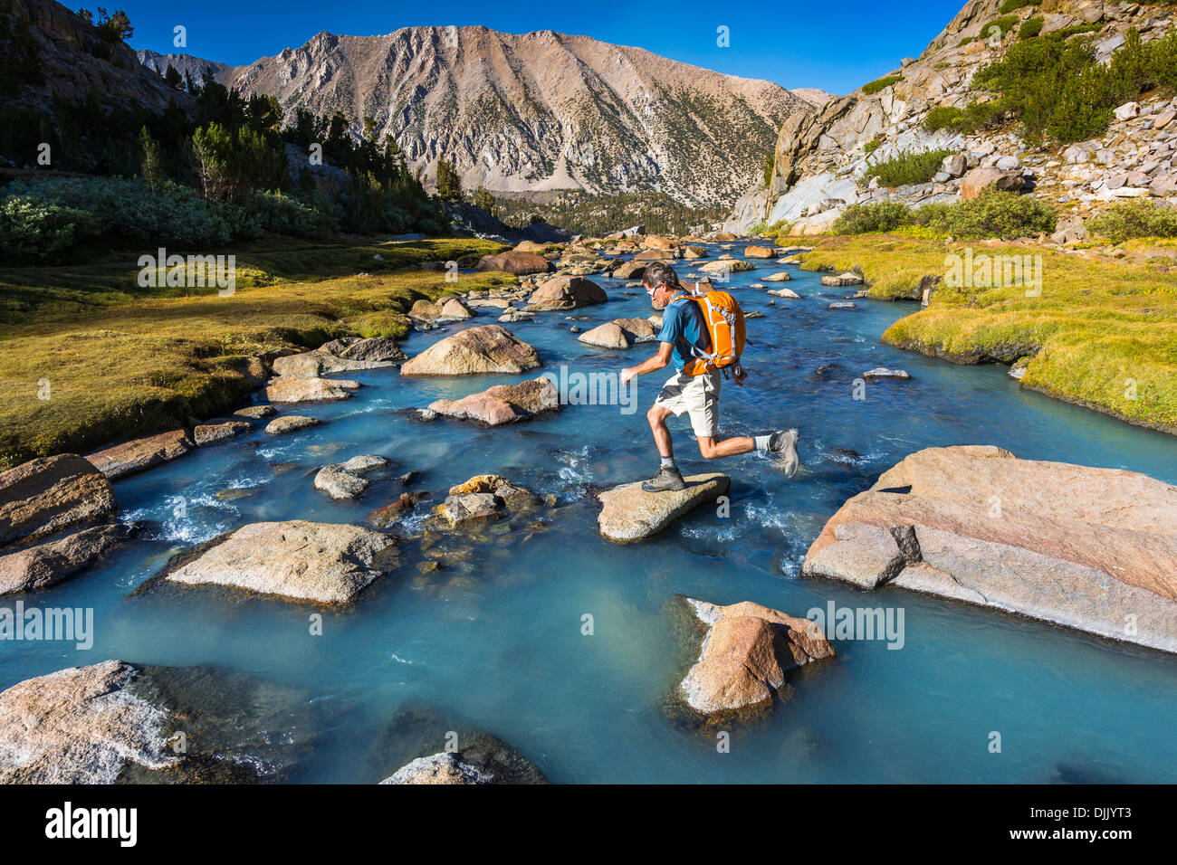 Hiker crossing stream in Sam Mack Meadow, John Muir Wilderness, Sierra ...