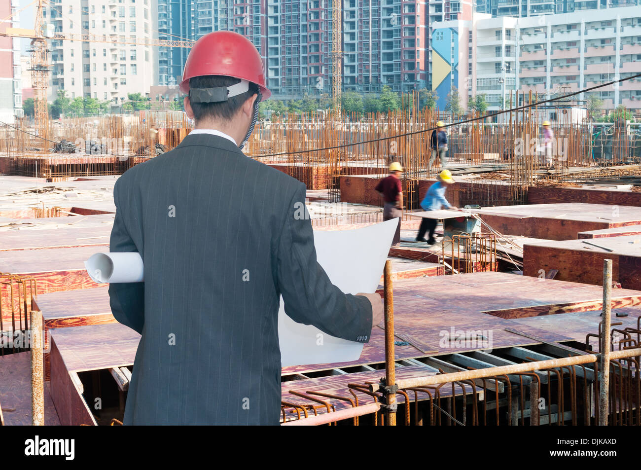 Rear view of architect looking comparing housing project with building ...