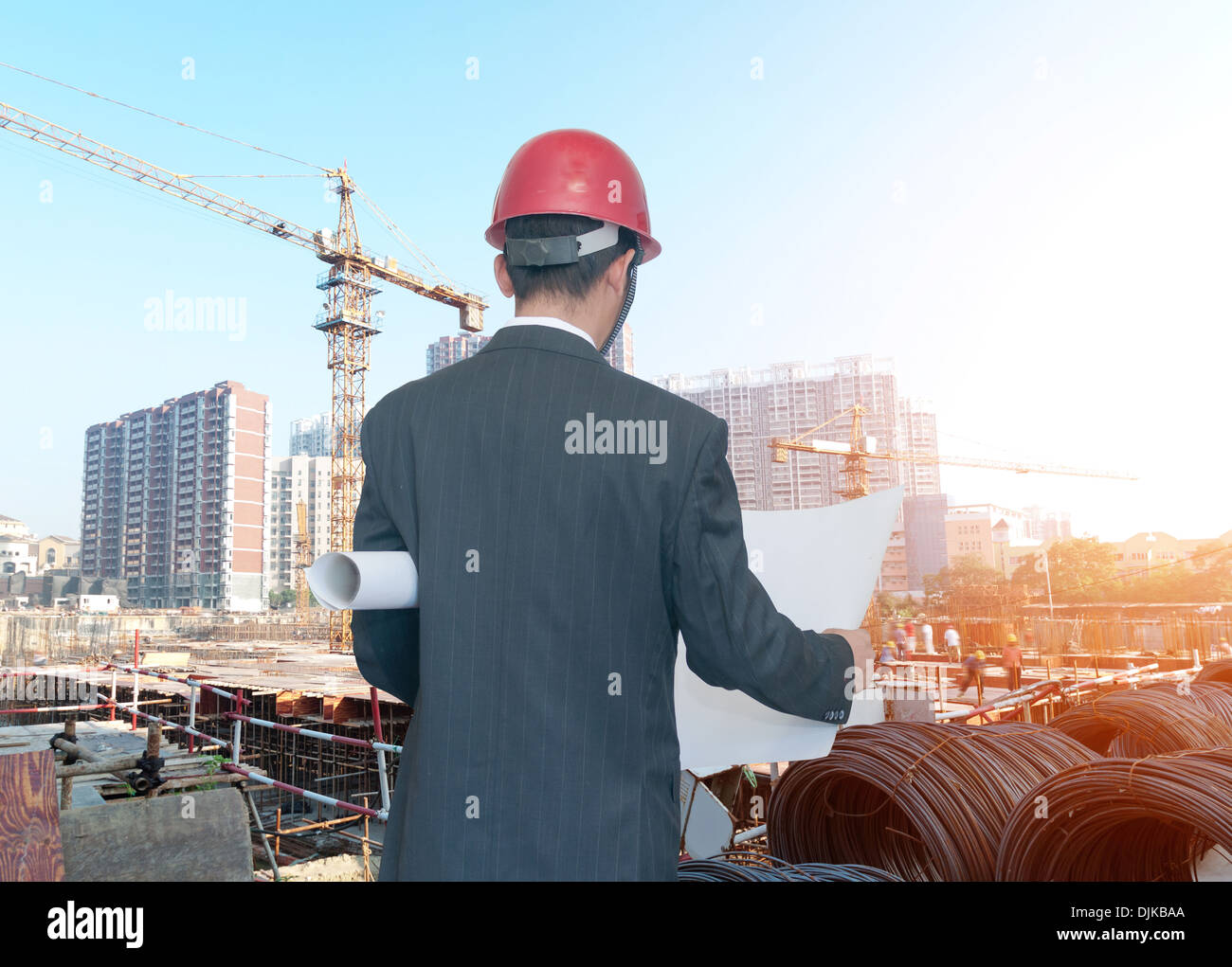 Rear view of architect looking comparing housing project with building ...