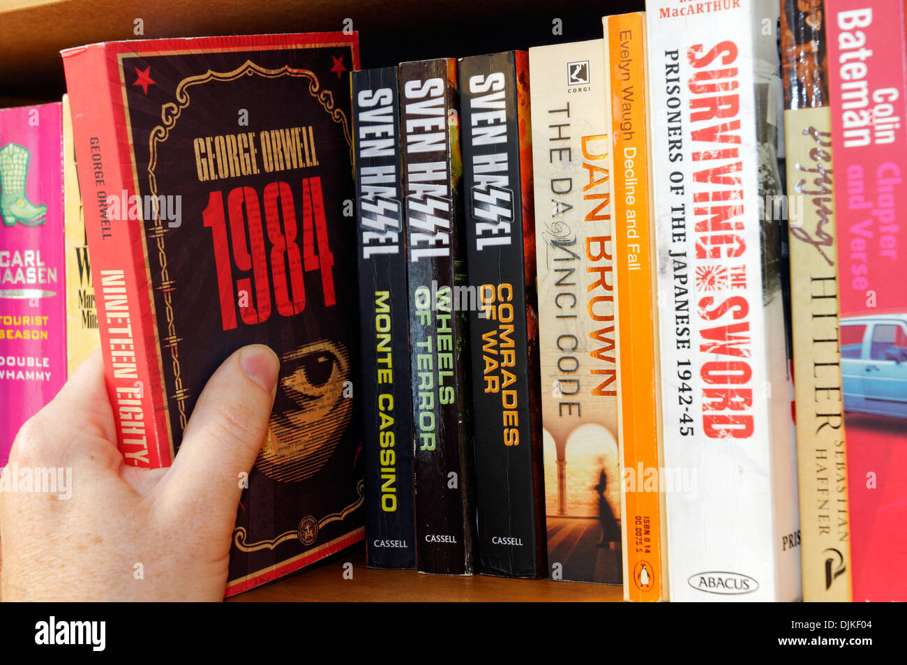 A hand taking George Orwell's 1984 from a bookshelf Stock Photo - Alamy