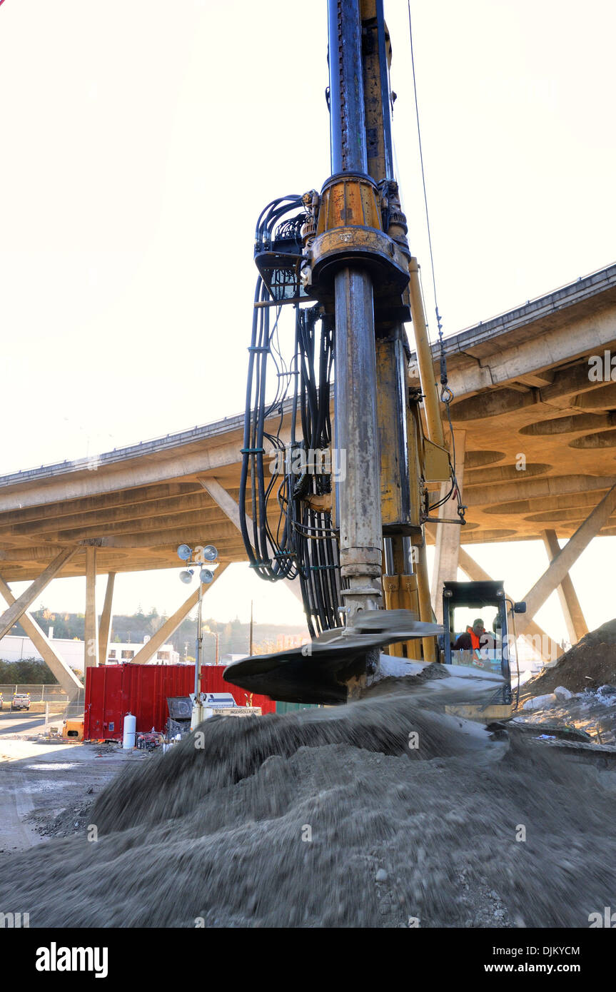 Large mobile construction drill with augur attached slinging dirt to ...
