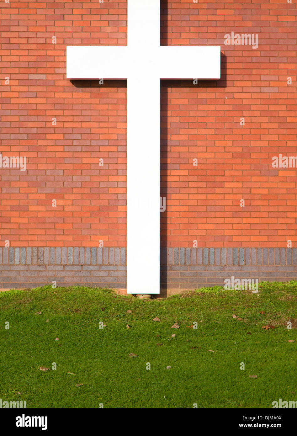 Large white crucifix cross against brick wall on grass lawn River of ...