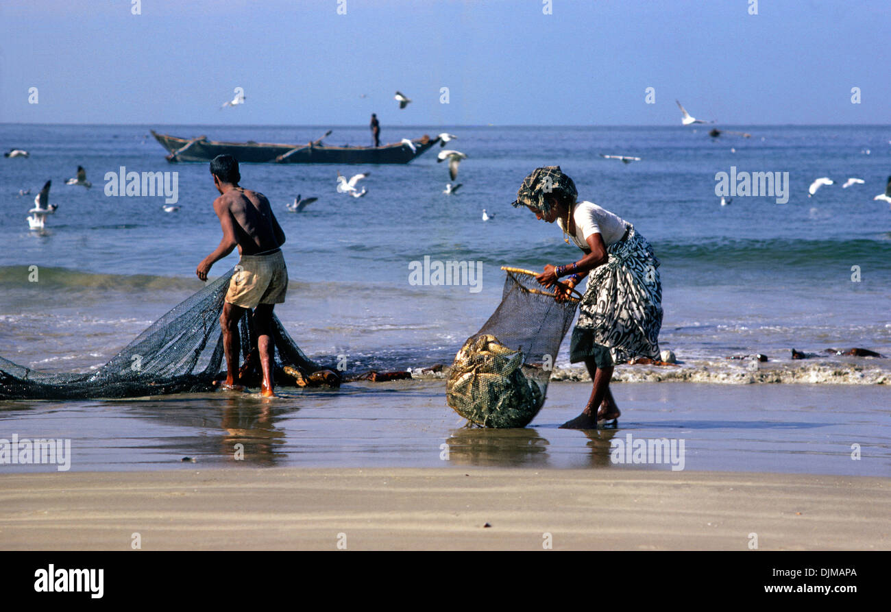 Woman and man sorting fishing nets on beach Goa India Stock Photo - Alamy