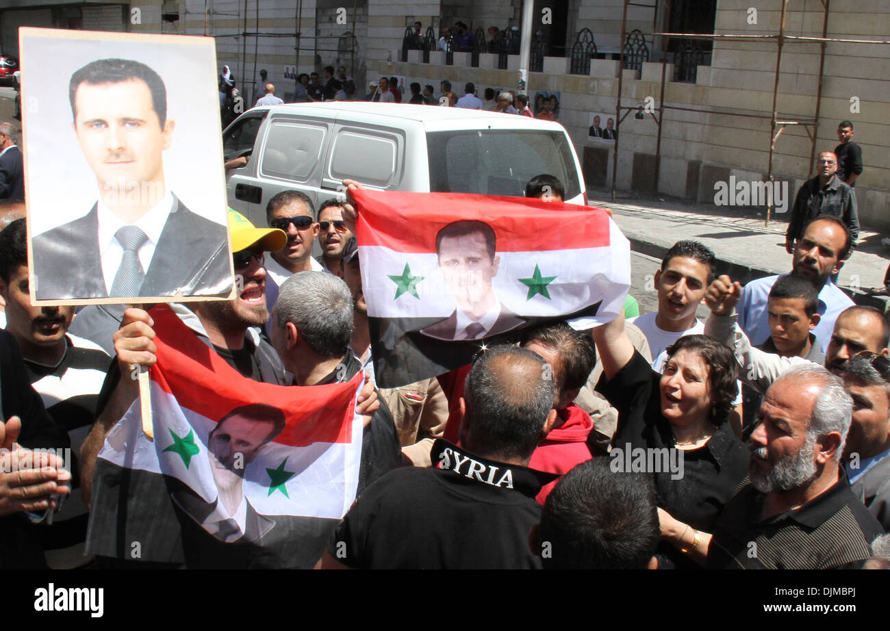 Syrians hold up national flags and posters of Syrian President Bashar ...