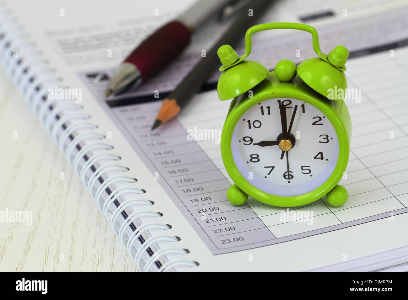 Miniature clock showing 9 am on open agenda Stock Photo - Alamy