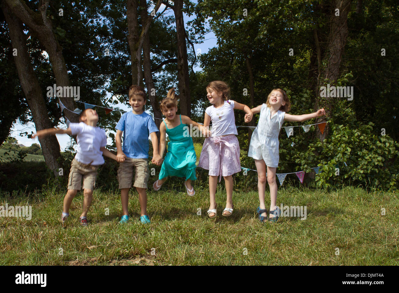 Children jumping in a line on a picnic in the long grass in Somerset ...