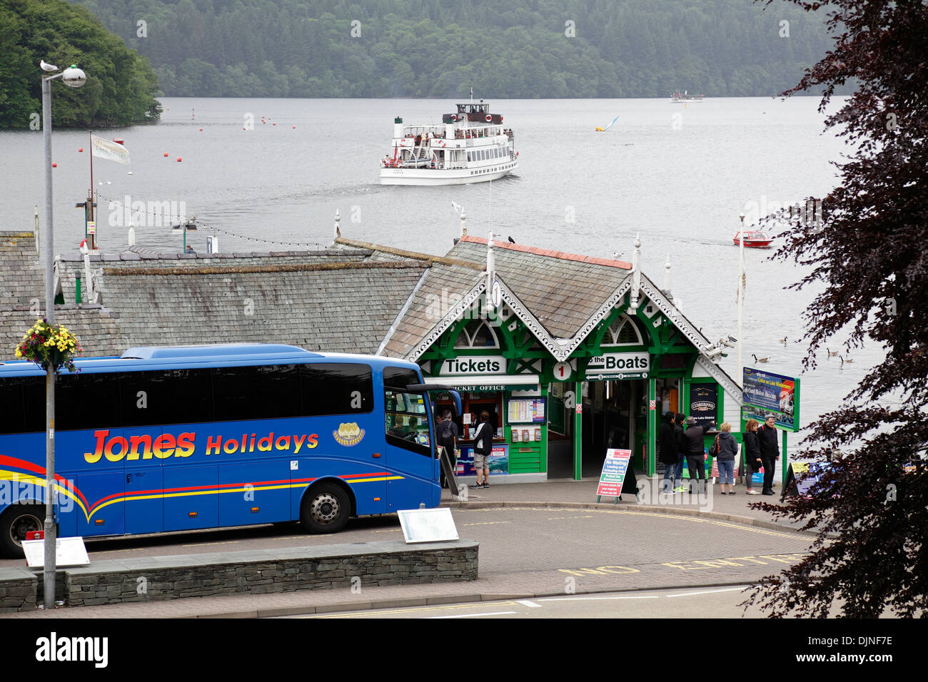 A tour bus beside a Ticket Office on the promenade at Lake Windermere ...