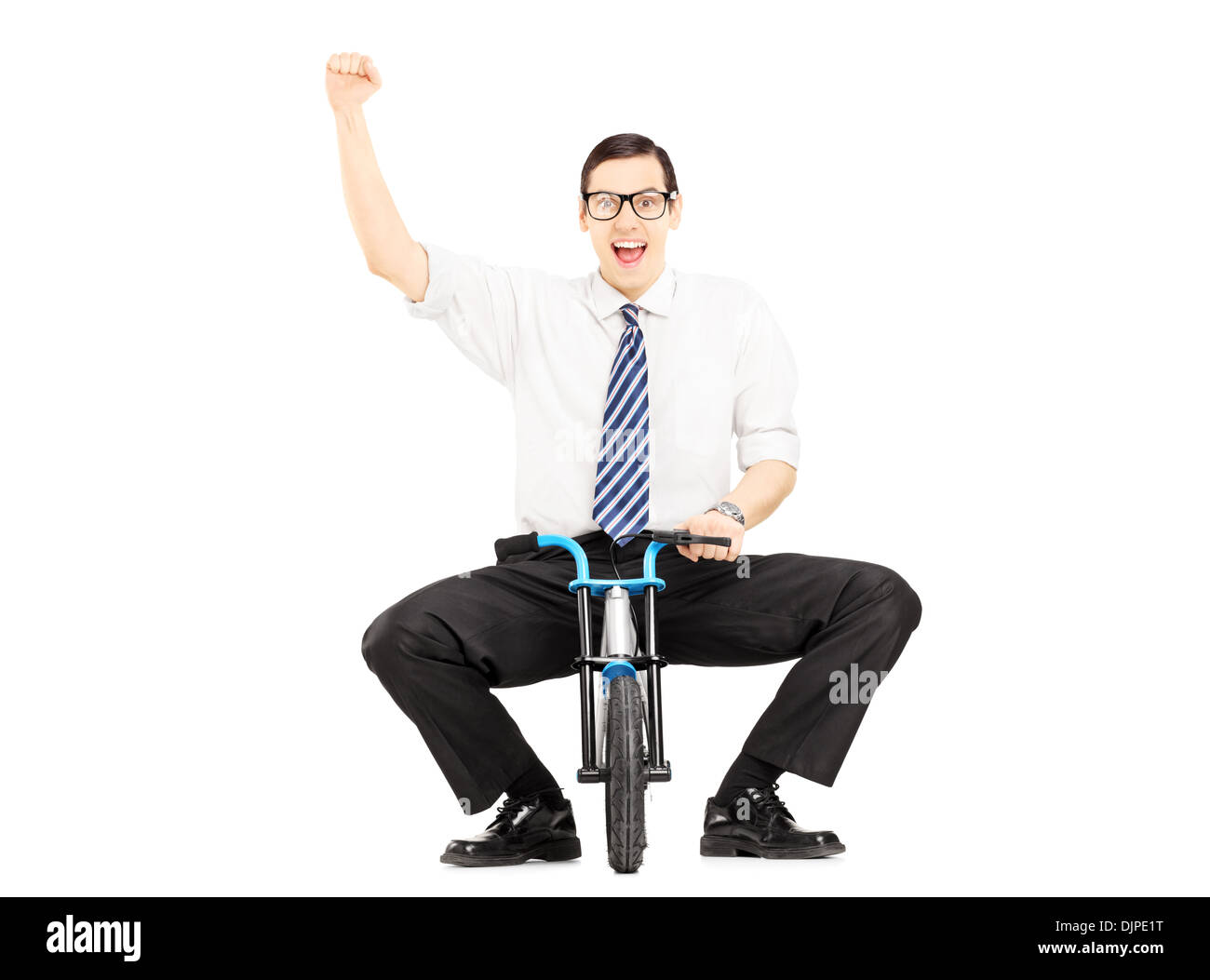 Excited young businessman riding a small bicycle and gesturing ...