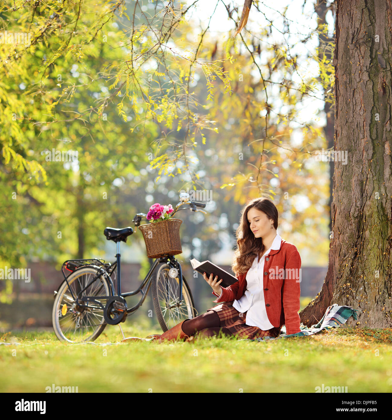 Young beautiful female with her bike, reading a novel in park Stock ...