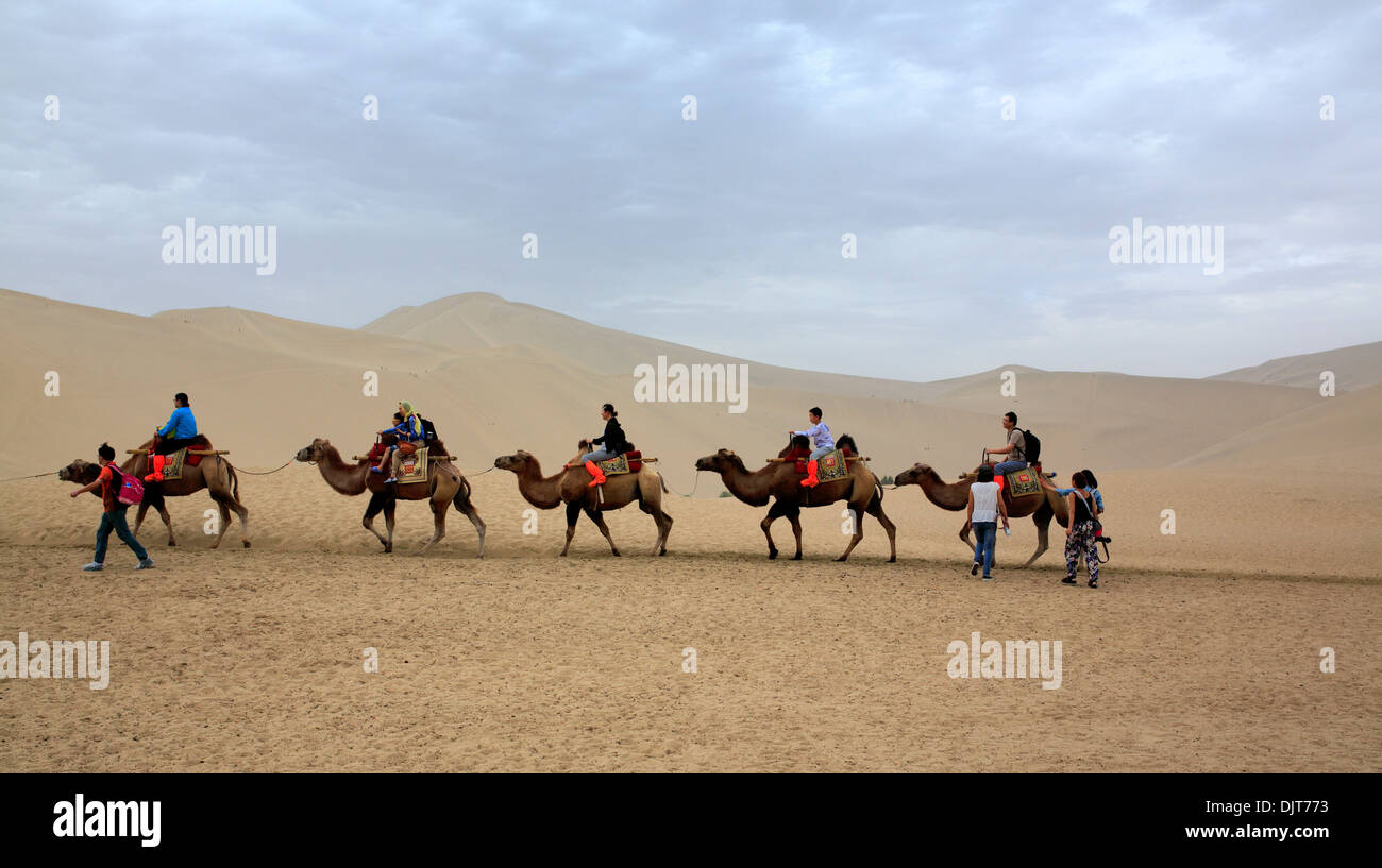 Camels riding near Crescent Lake, Dunhuang, Gansu province, China Stock ...