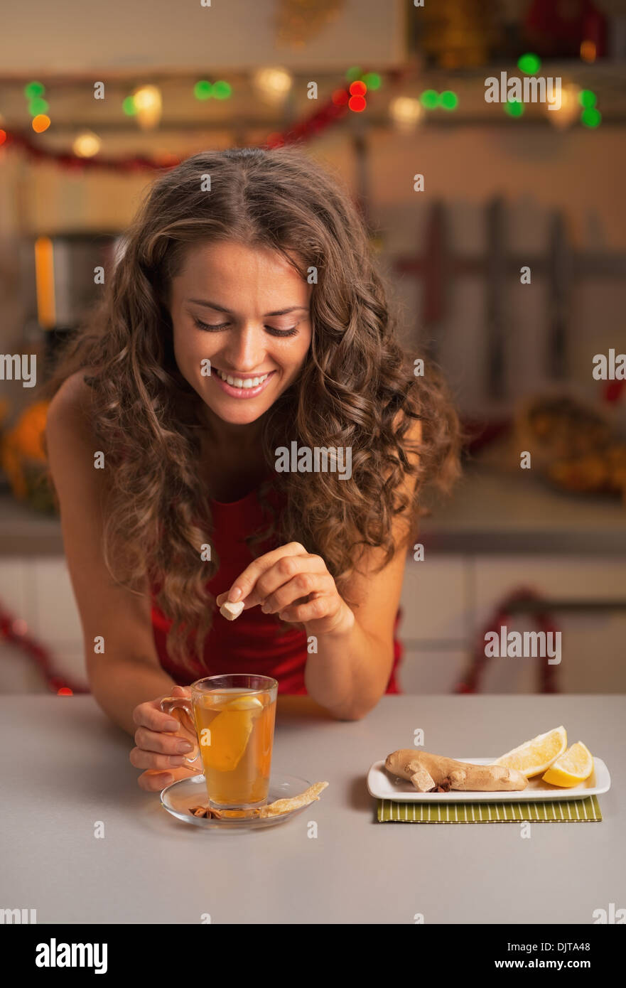 Happy young woman putting brown sugar cube into ginger tea Stock Photo ...