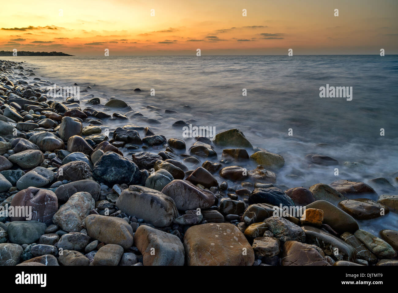 Sunset over pebble beach with motion blurred sea surface Stock Photo ...
