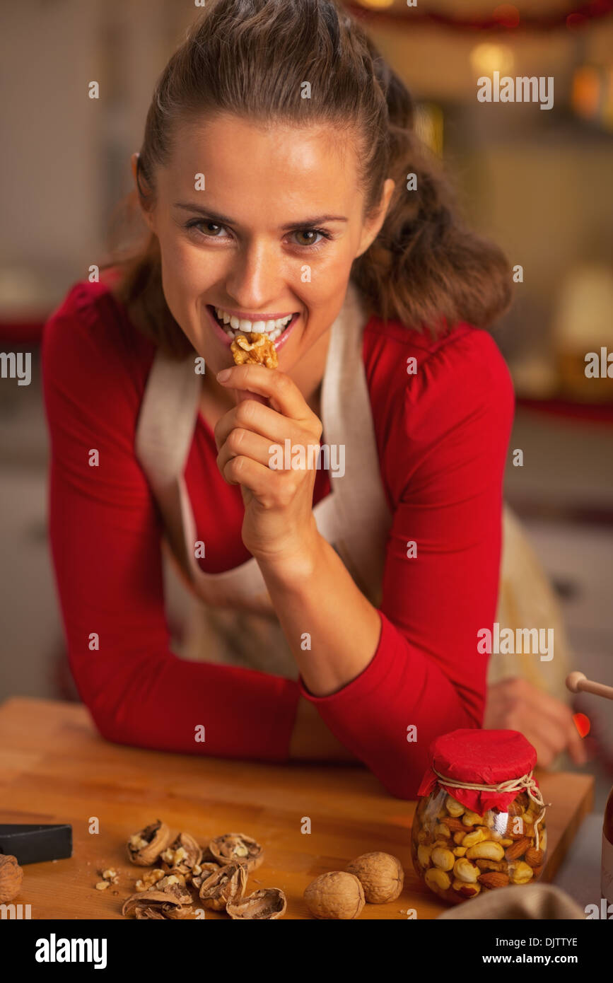 Happy young woman eating walnuts in kitchen Stock Photo - Alamy
