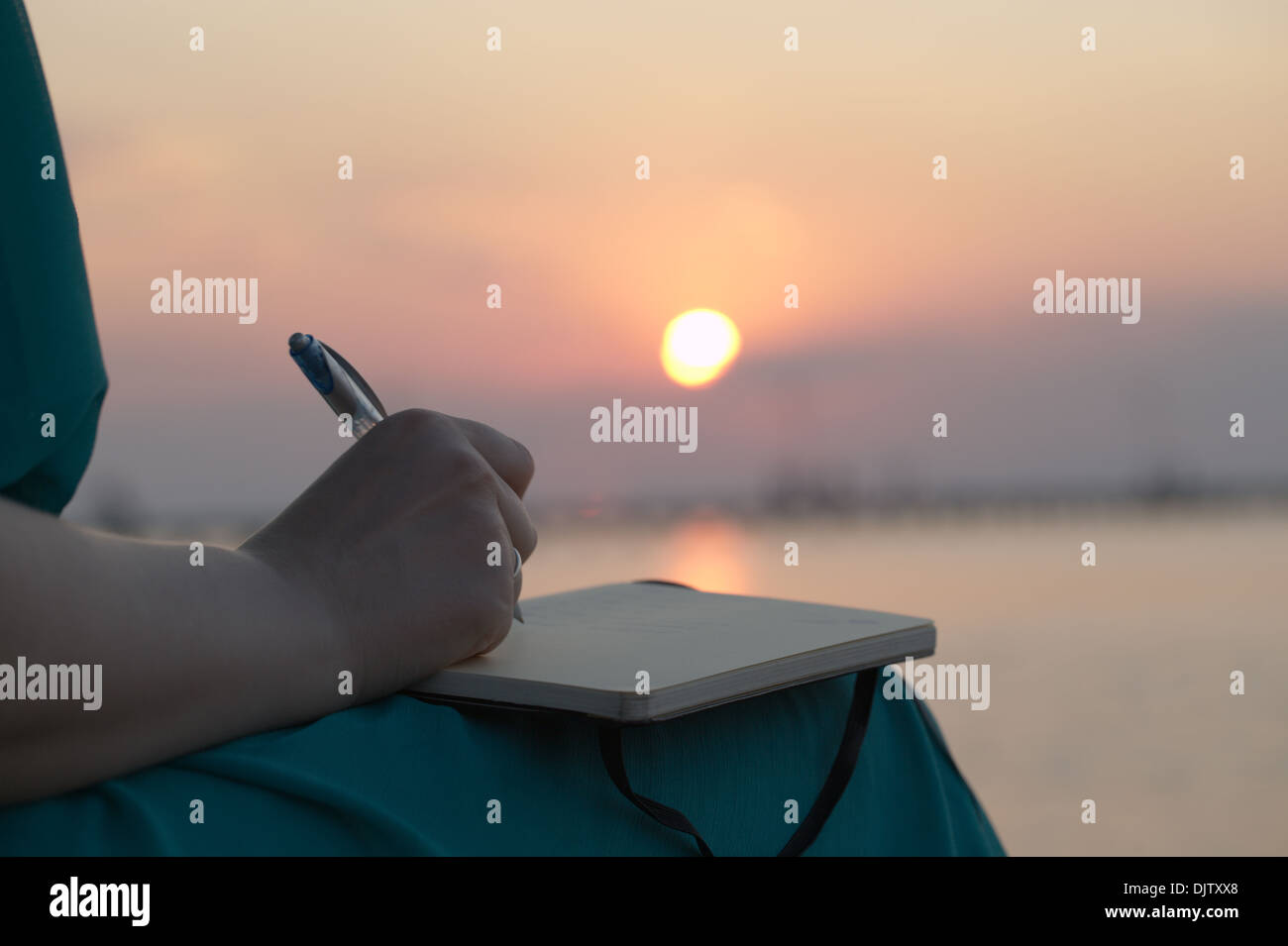 Woman writing in her diary at sunset Stock Photo - Alamy