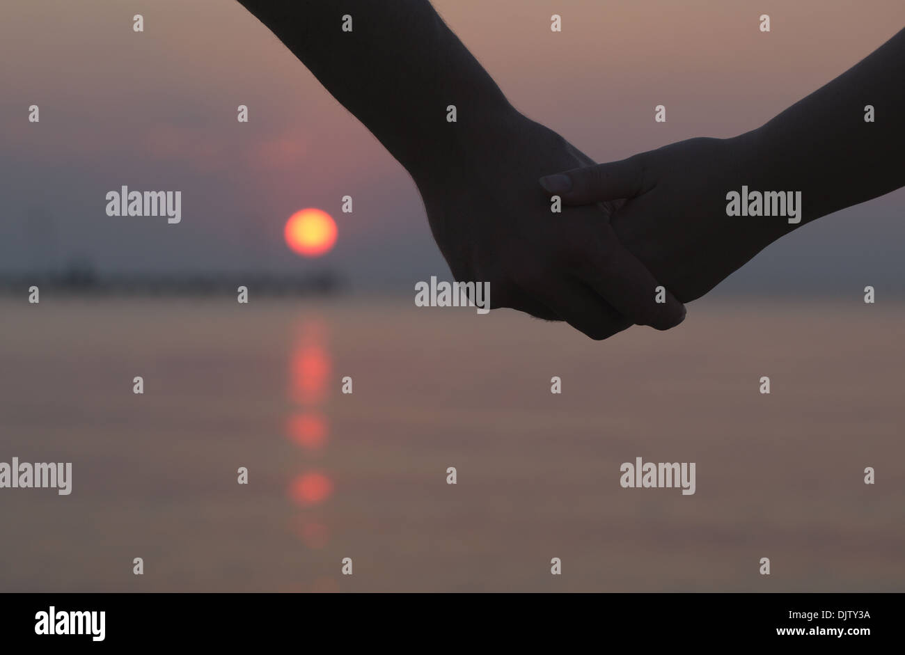 Couple holding hands at sunset Stock Photo - Alamy