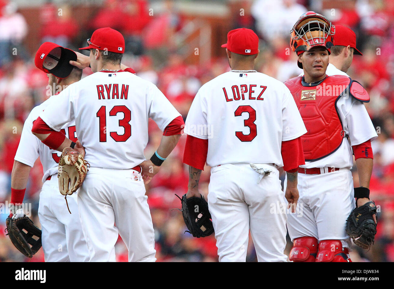 Members of the Cardinals infield wait at the pitching mound while a new ...