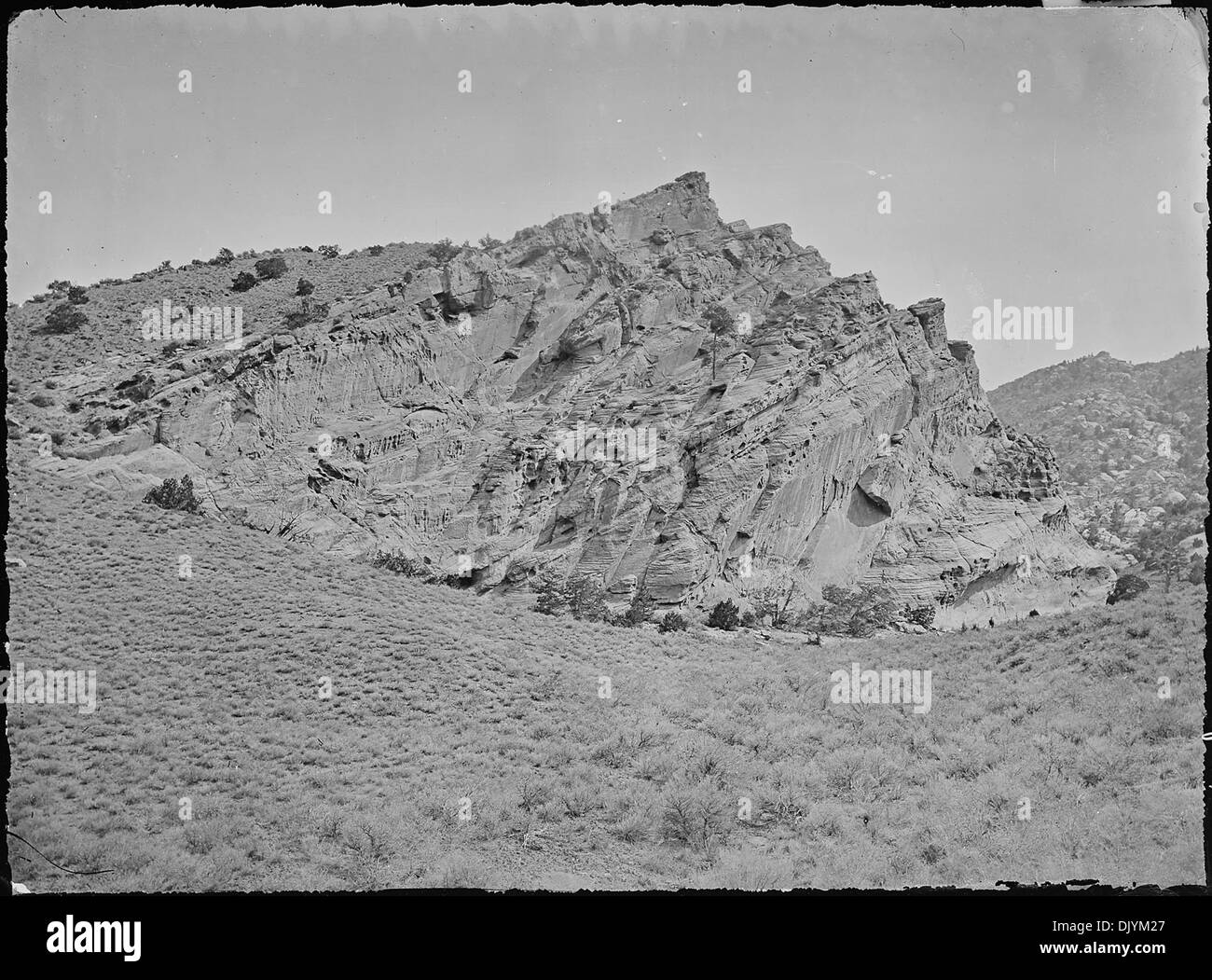 This image features a perpendicular bluff of weathered sandstone ...