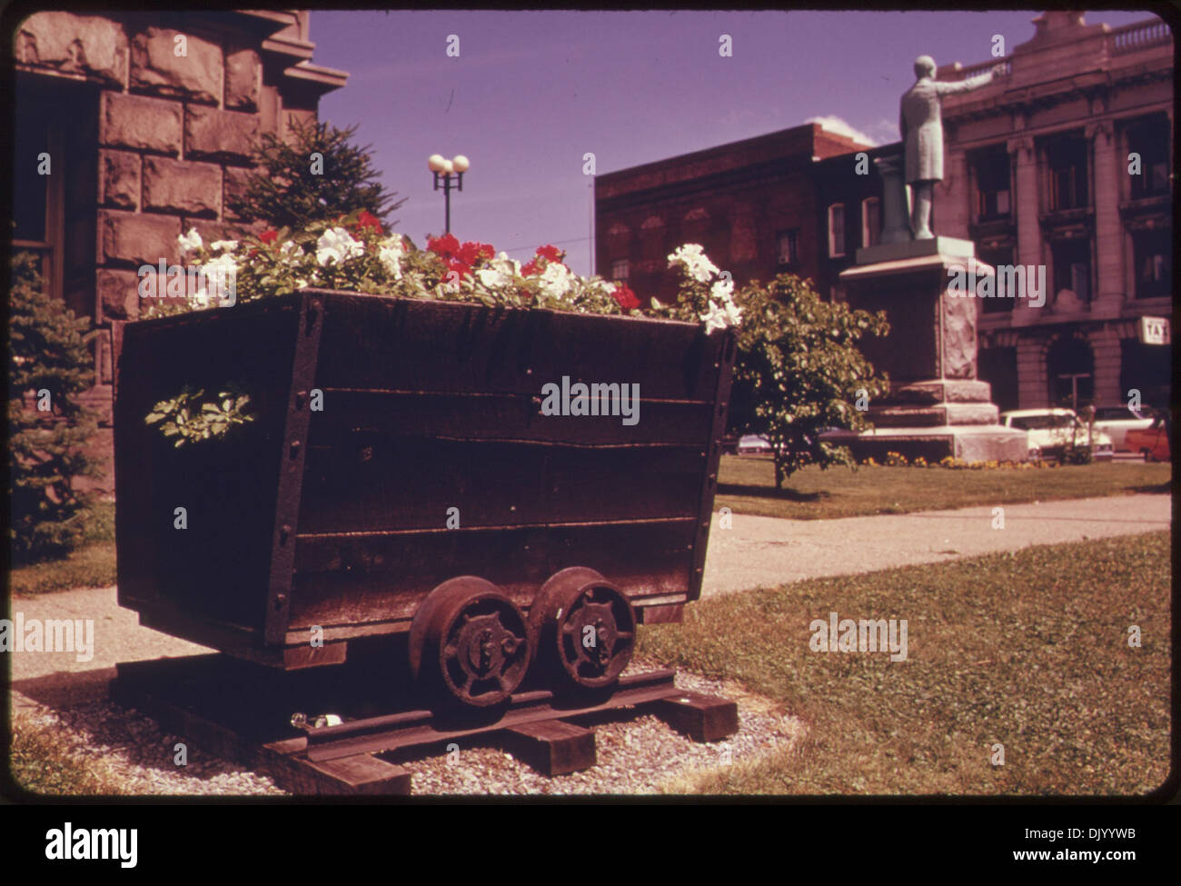 A coal car flower planter placed in front of a town hall signifies the ...