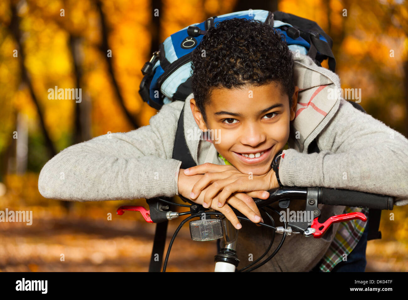 Close portrait of the nice black 10 years old boy laying on the bicycle ...