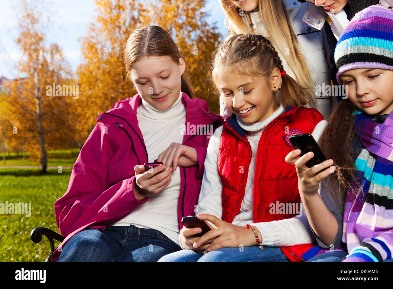 Close portrait of school age teen kids looking at their mobile phones ...
