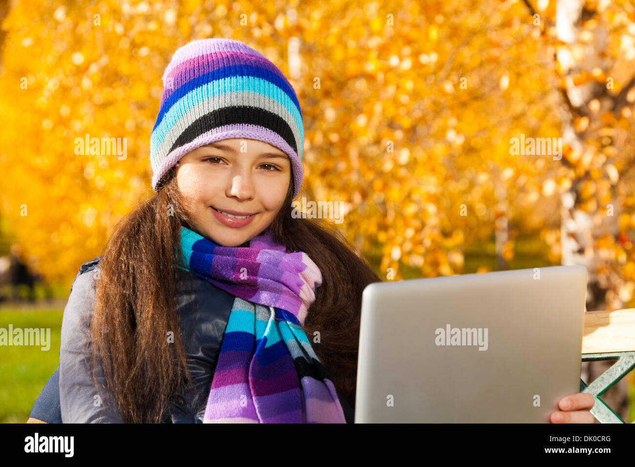 Girl with tablet computer 11 years old sitting in the park on sunny ...