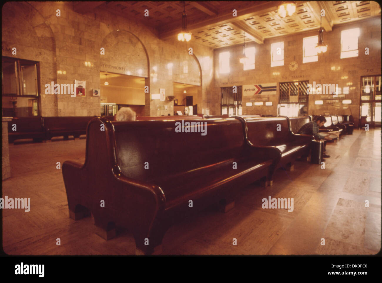 Massive wooden benches are featured in a railroad terminal, reflecting ...