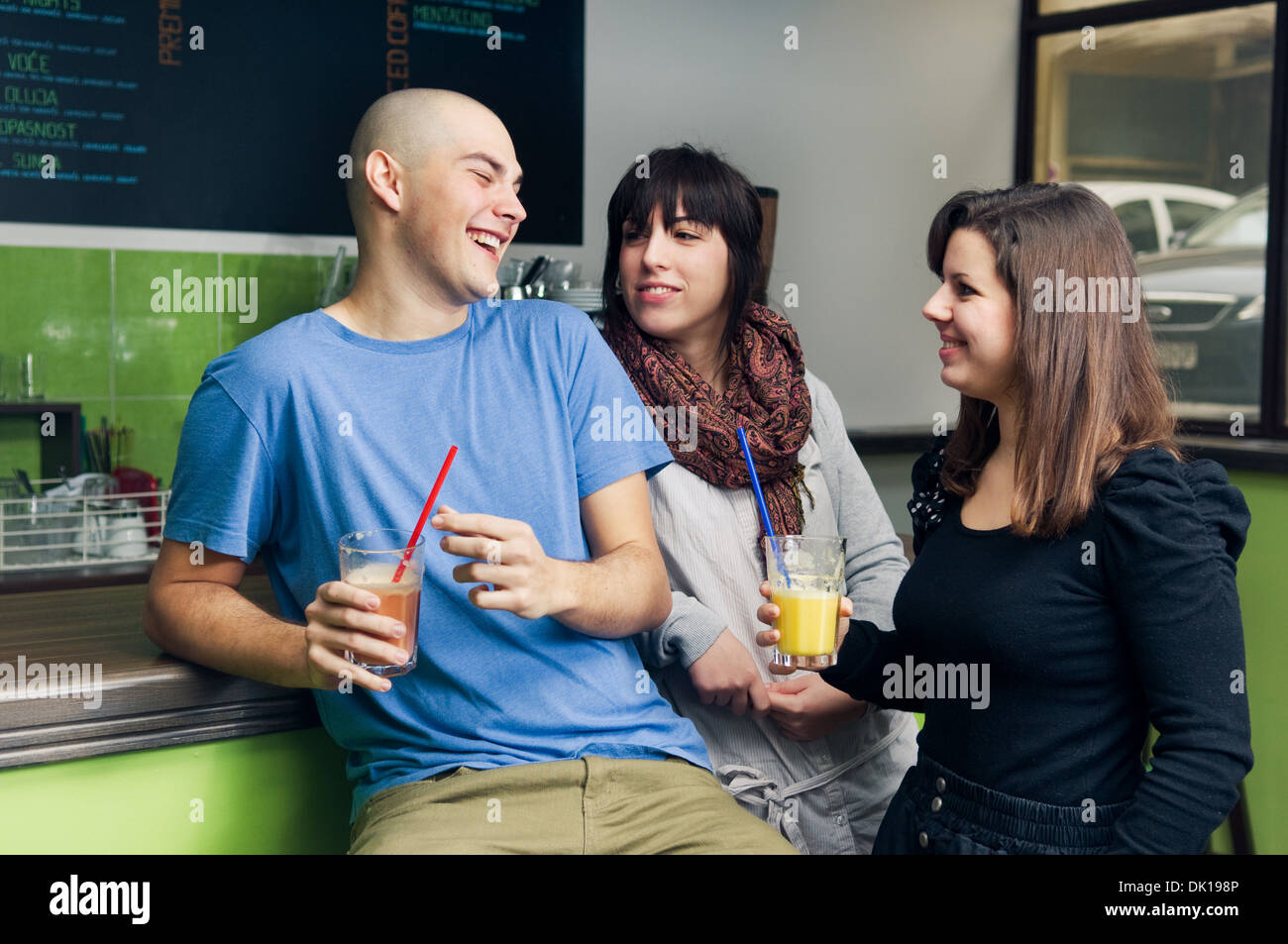 Three young friends having fun in cafe. Drinking smoothies Stock Photo ...
