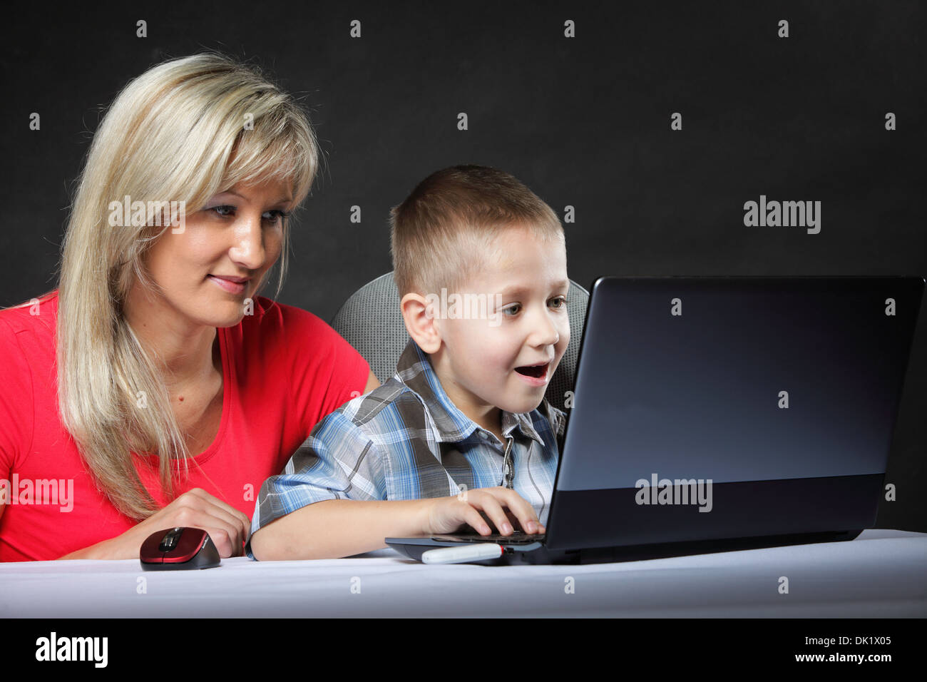 mother with son together looking on the laptop computer black ...